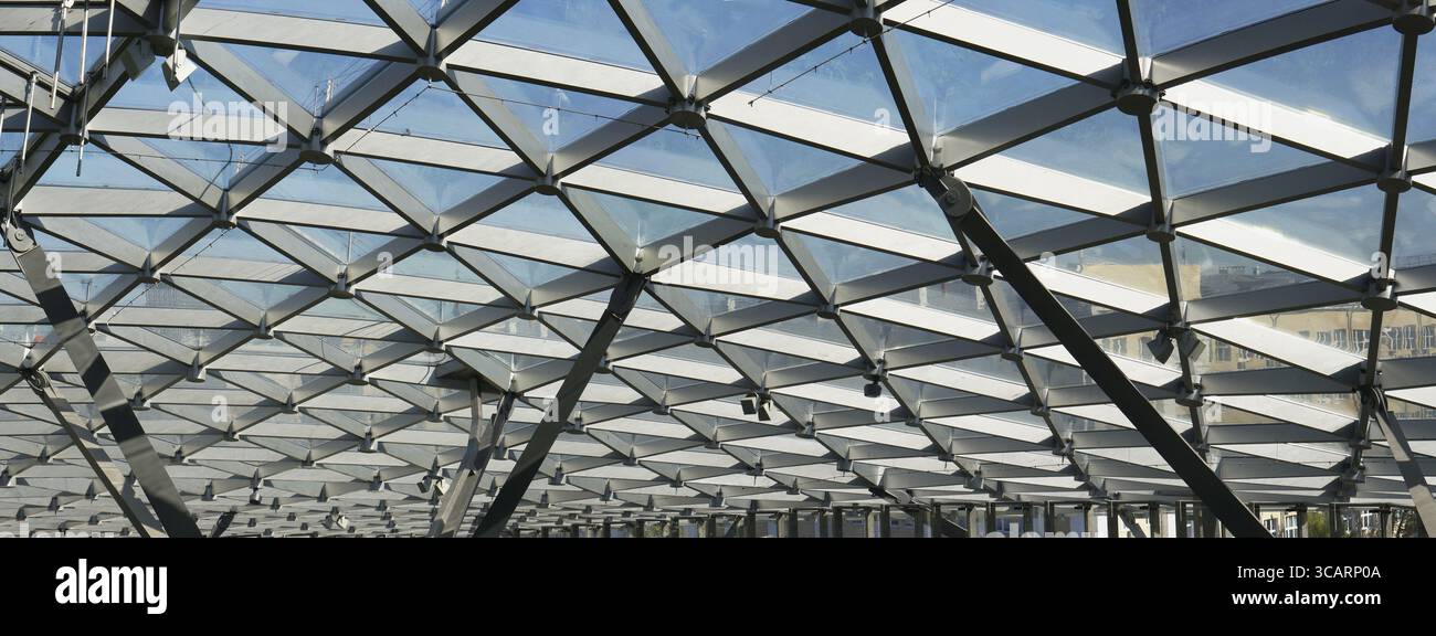 The glass ceiling of the modern building supports a steel beams grid ...