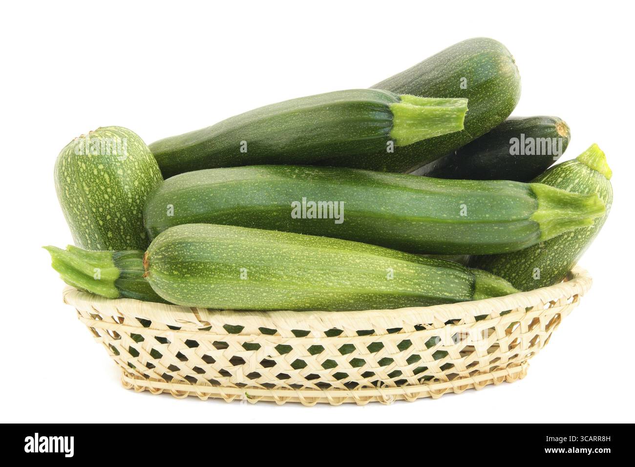 Fresh small green vegetable marrows in a wattled small basket. Isolated ...