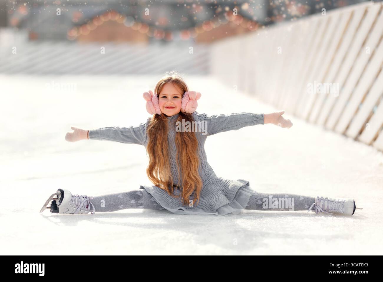 Girl child figure skater skating in splits on the rink in winter during ...
