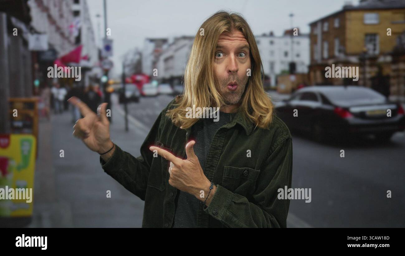 Blond man with long hair points both fingers to storefront on busy ...