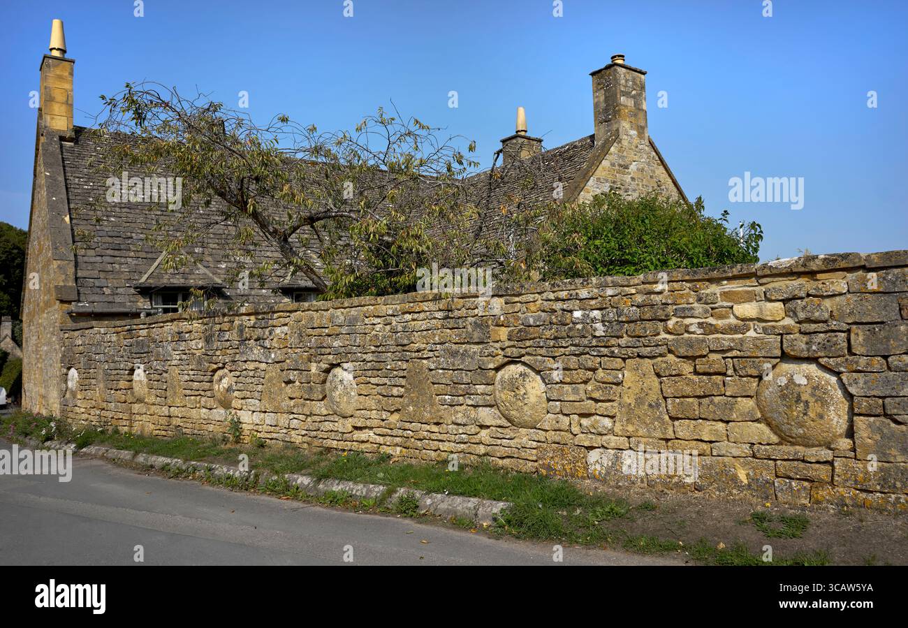 Unusual and decorative Cotswold stone wall with circular staddle stones ...