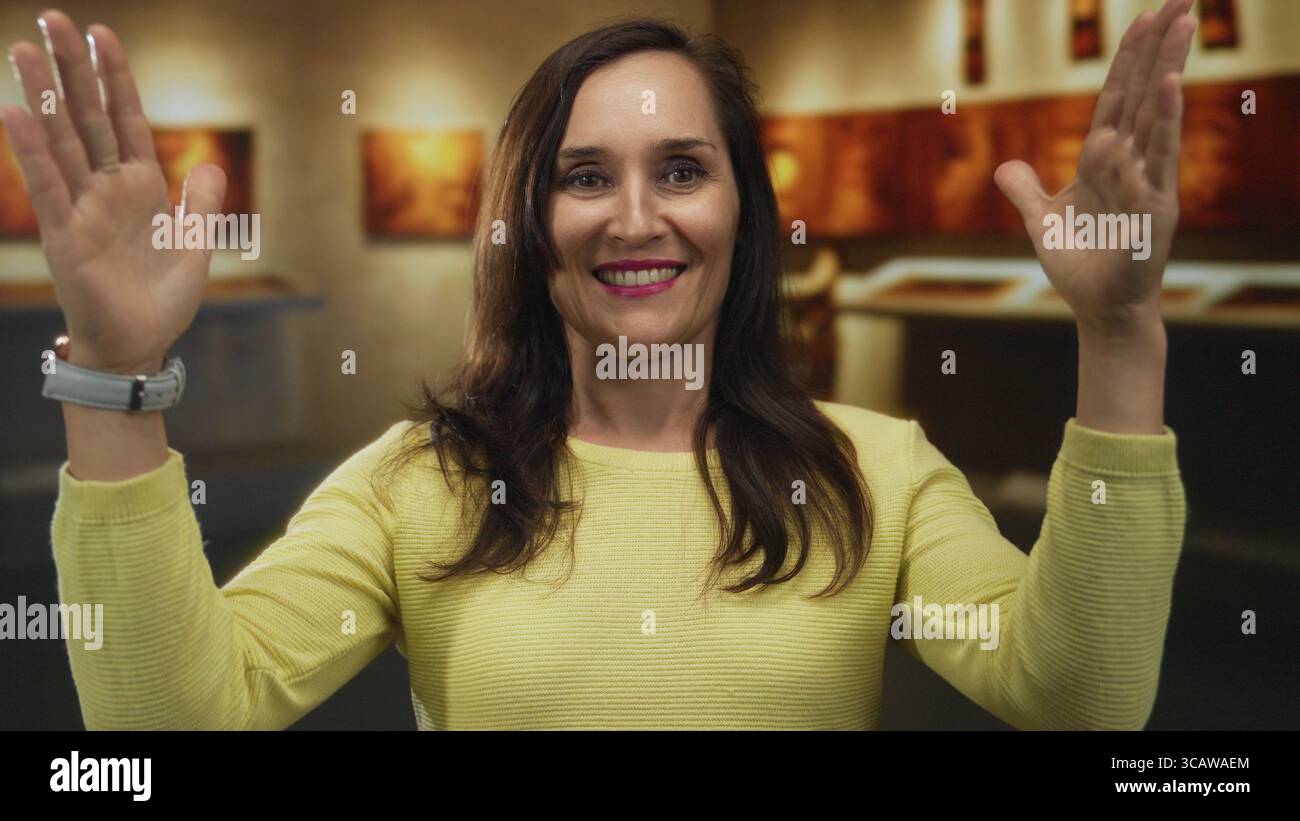 Young hispanic woman showing large hand span gesture in an art museum ...