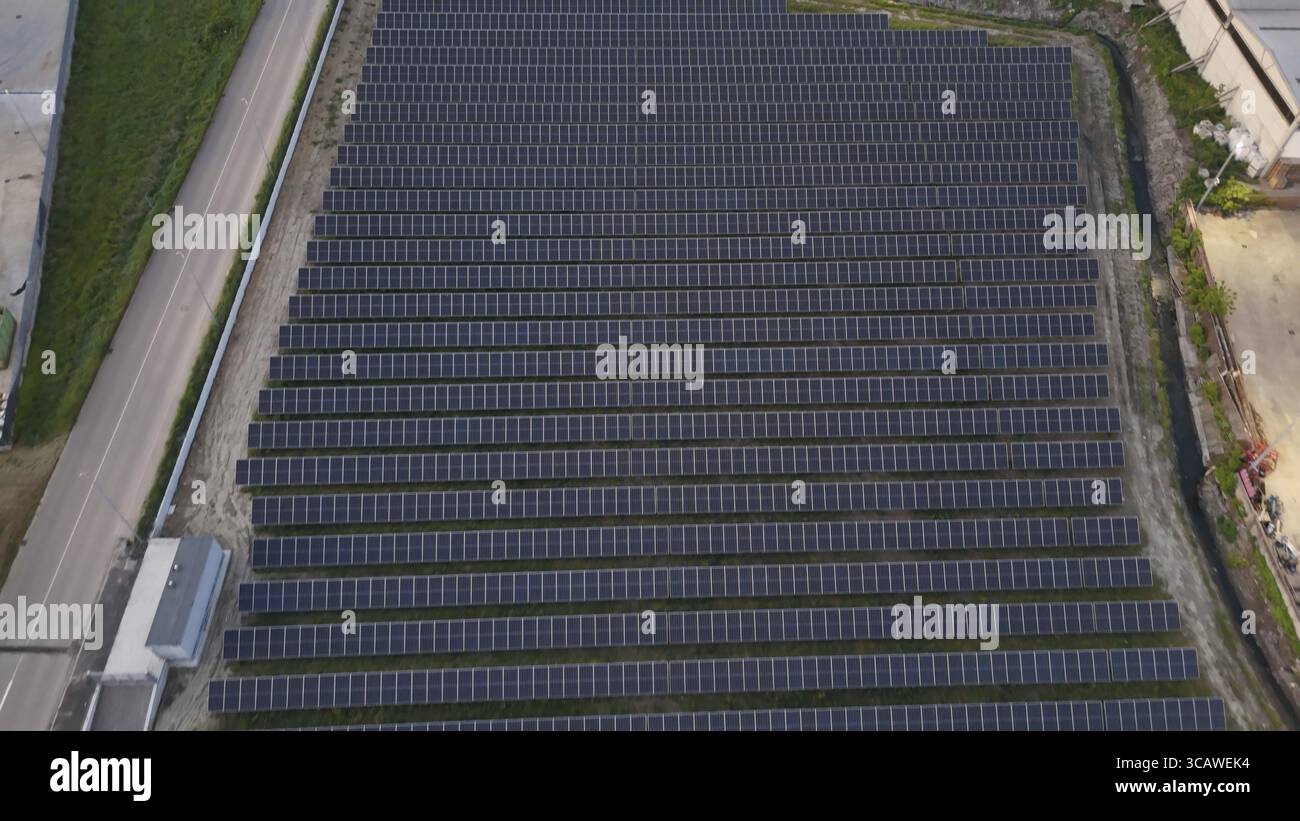 Rows of solar panels stand in a field, soaking up the sun's rays and ...