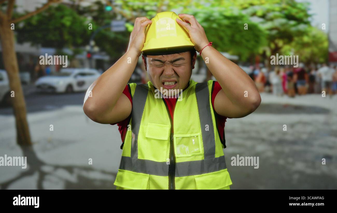 Young man wearing safety vest and helmet looking stressed on bustling ...