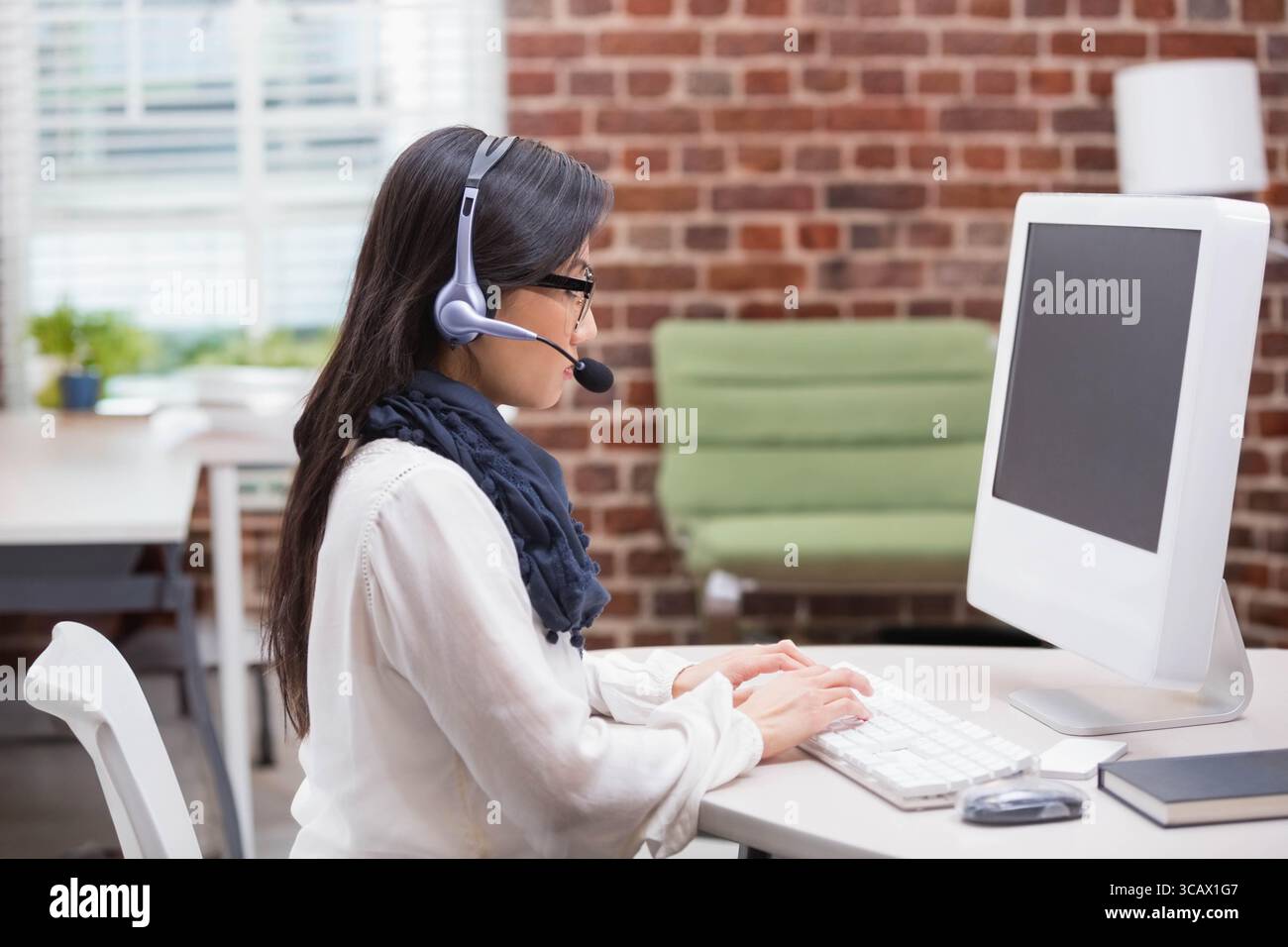 Customer support agent is typing at white desk in modern office, with ...