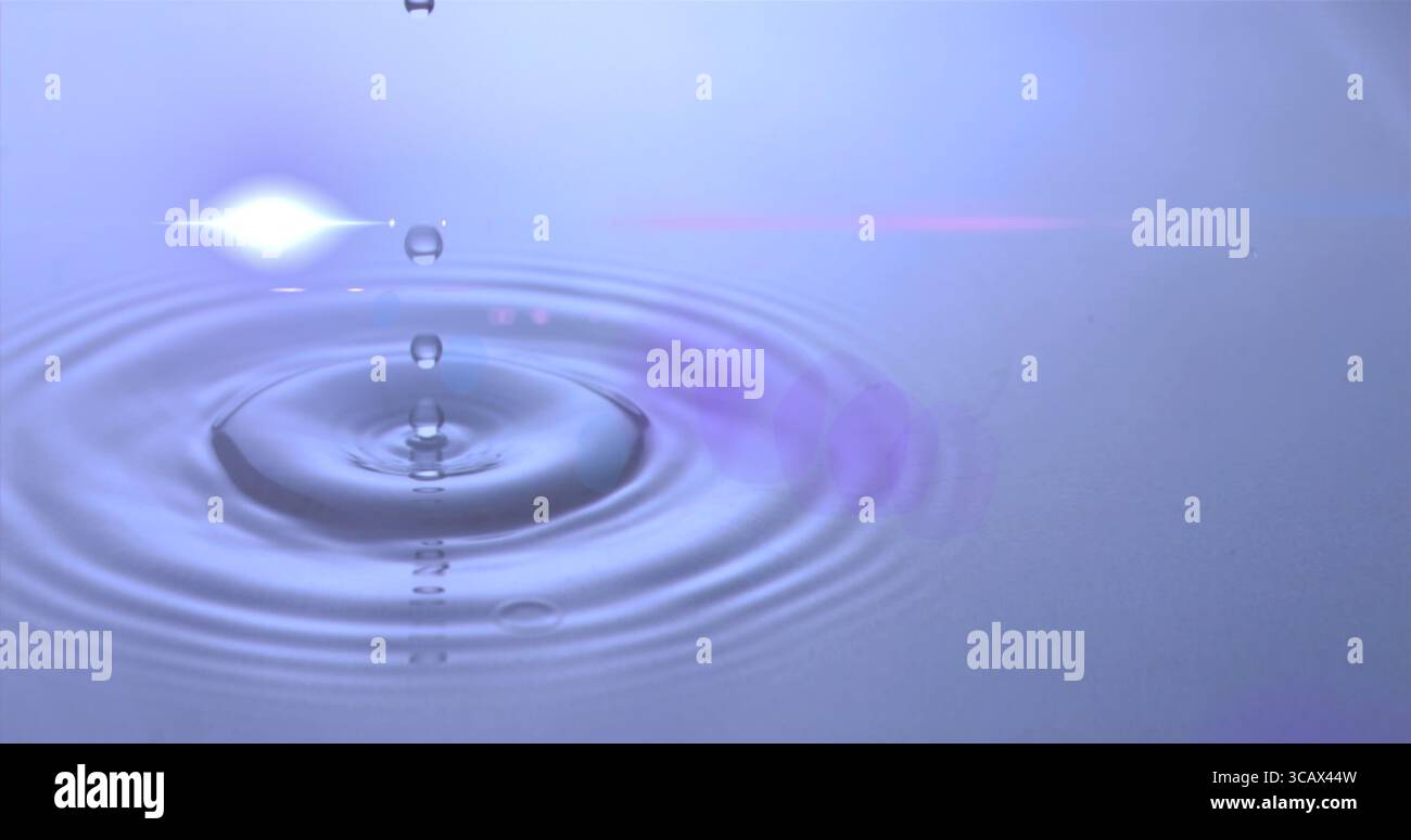 Hovering water droplet creating concentric ripples on calm water ...
