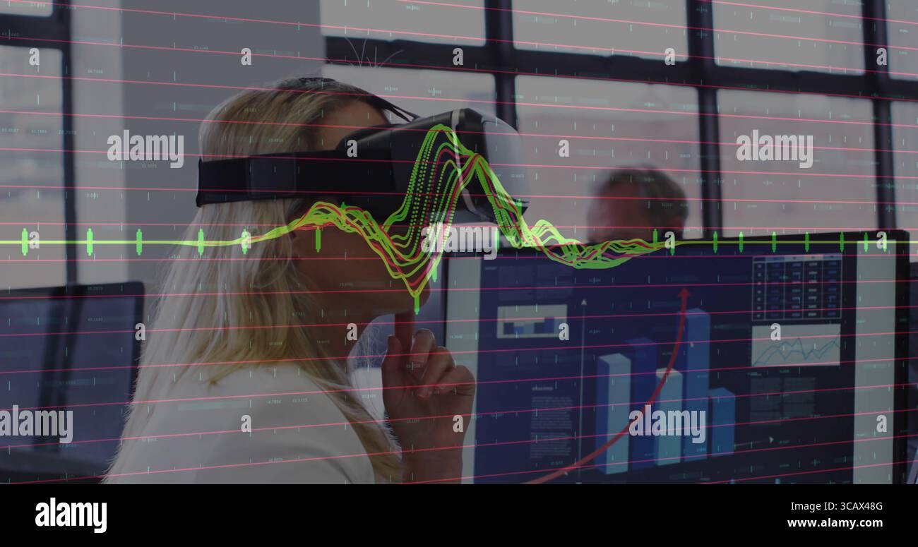 Woman wearing blazer and VR headset analyzing data using dual monitors ...