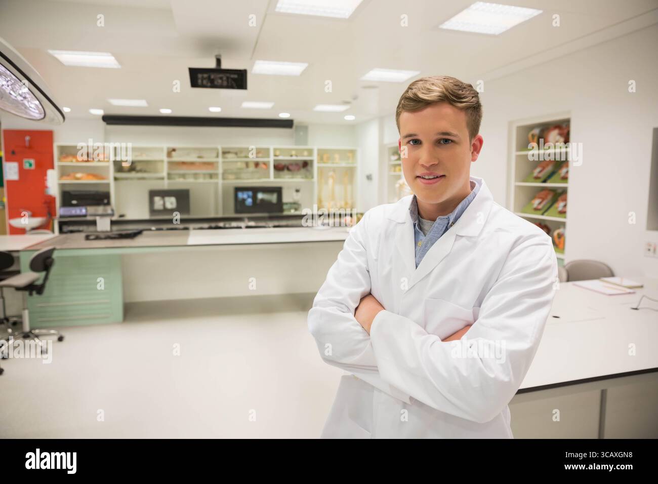 Male researcher wearing lab coat with arms crossed at medical lab near ...