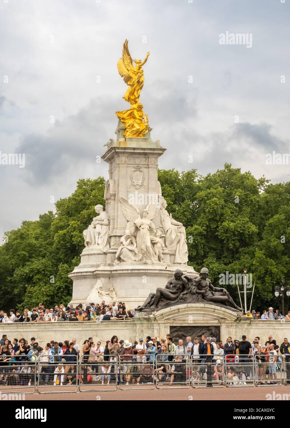 A large crowd of tourists gathers around the Queen Victoria Memorial in ...