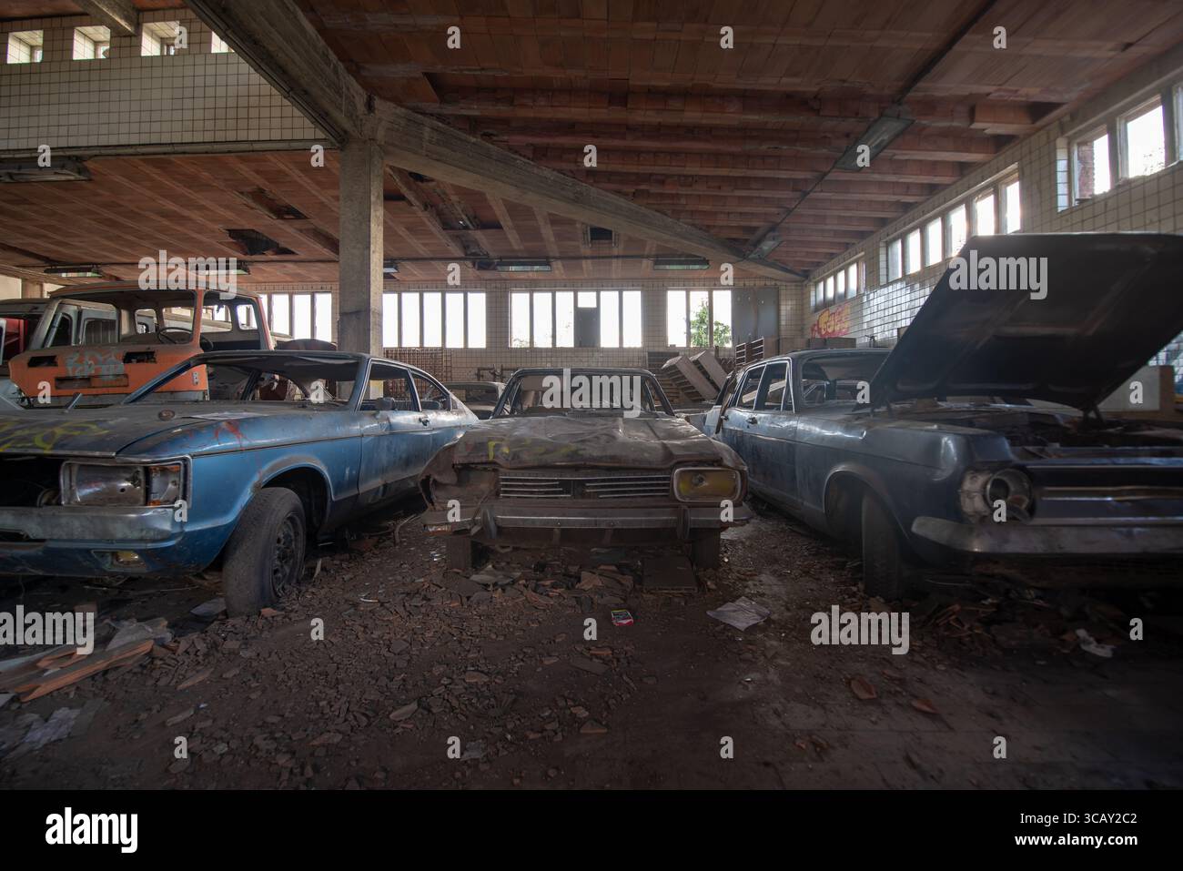 Abandoned vintage cars in a decaying industrial warehouse with natural ...