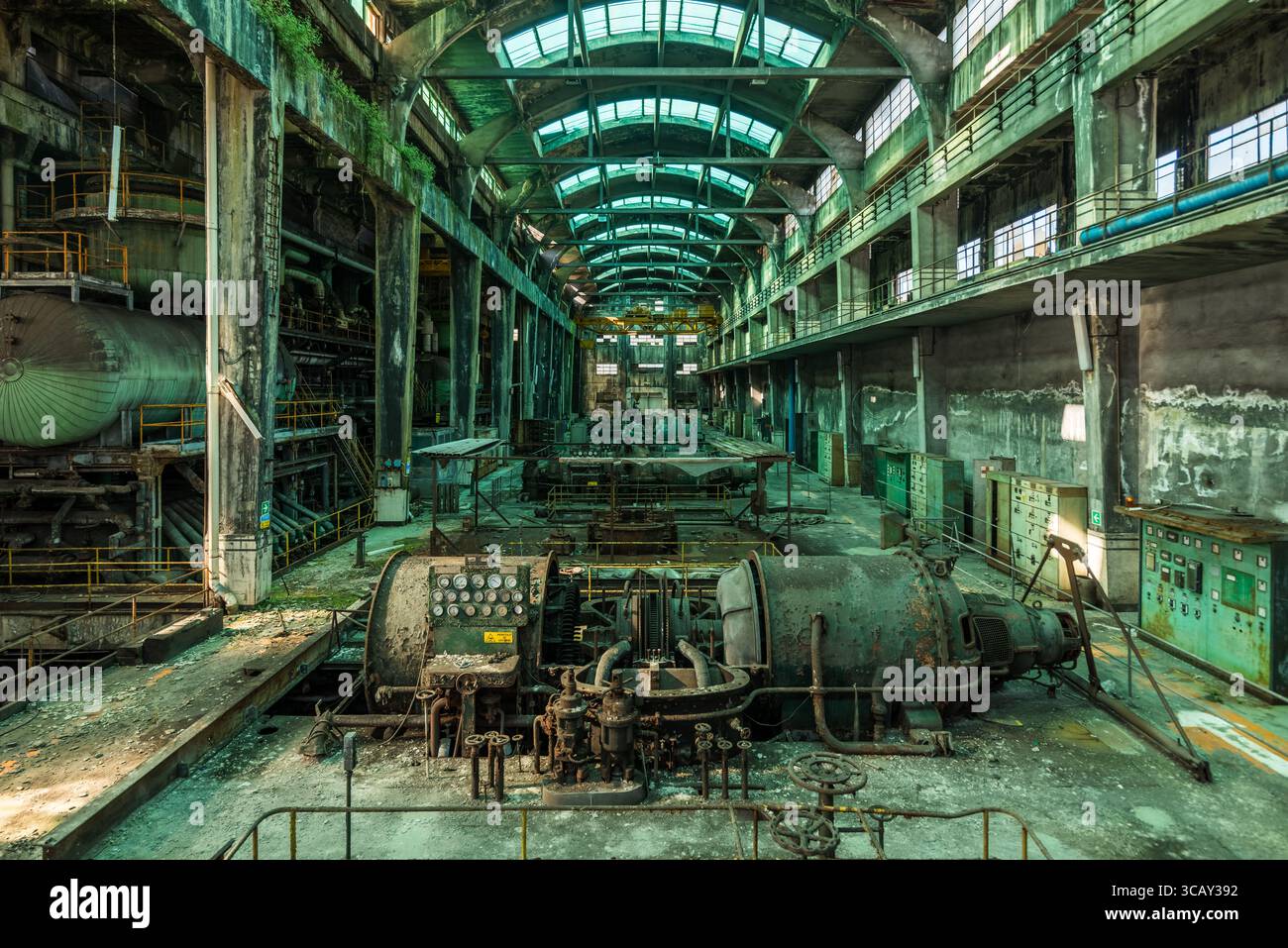 Abandoned industrial factory interior with rusted machinery and green ...