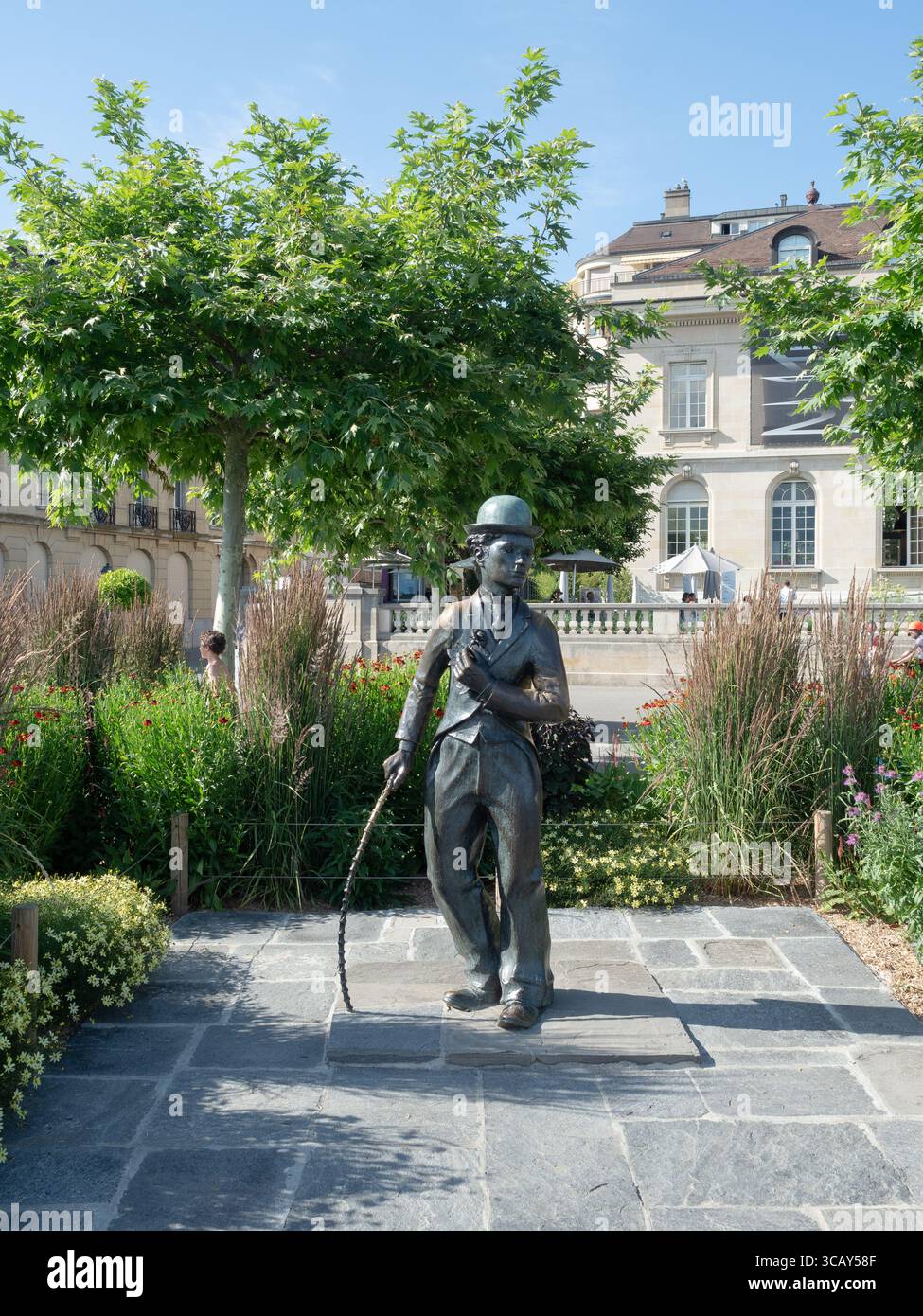 Bronze statue of Charlie Chaplin in a sunny garden with historic ...