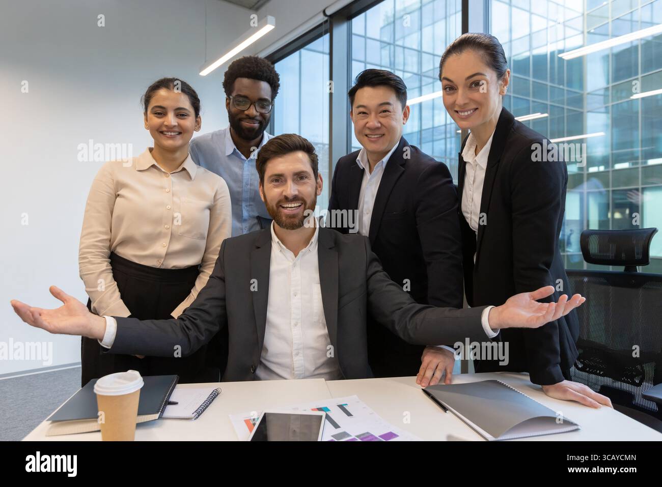 A group of professional team members smile and pose in a modern ...