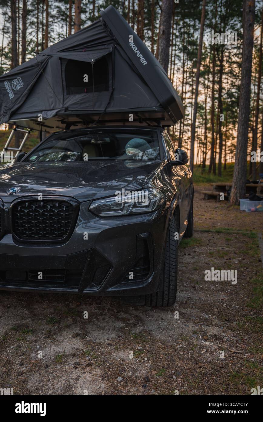 BMW X4 2025 with Rooftop Tent in Forested Camping Area at Sunset Stock ...