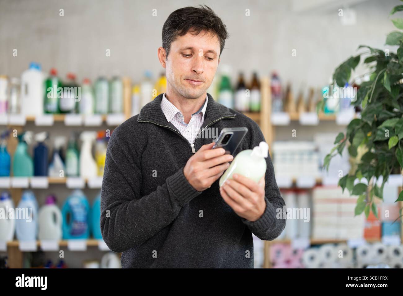 Middle-aged woman scanning QR-code on detergent at supermarket Stock ...