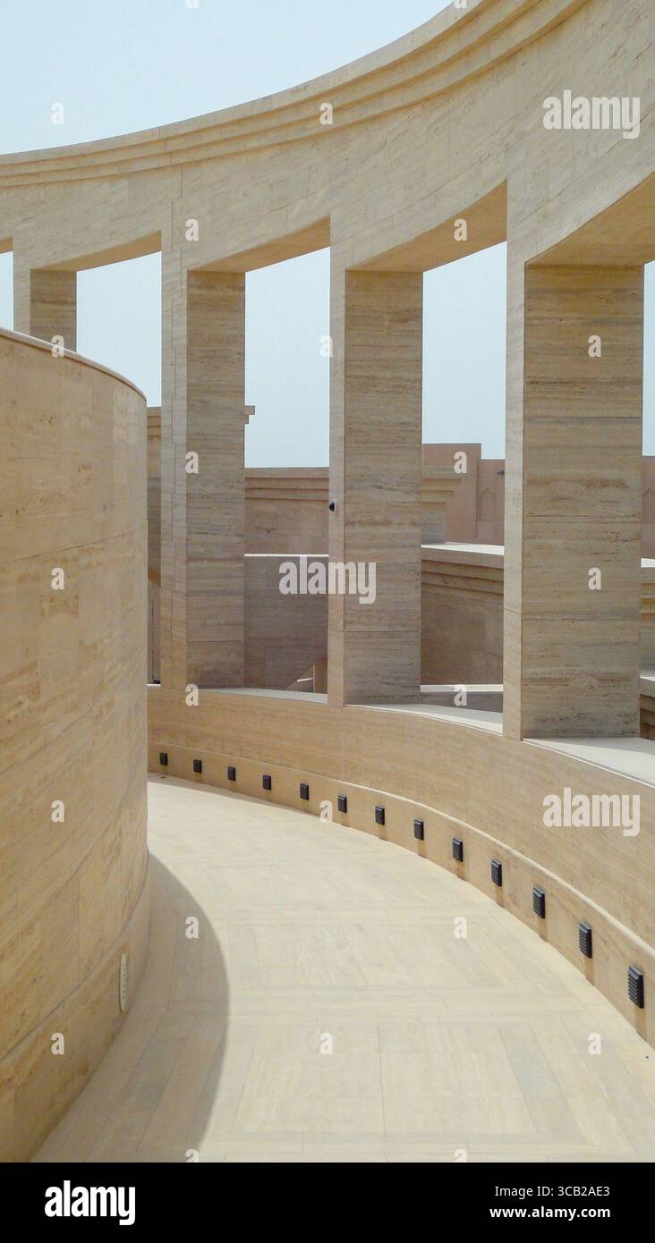 A curved walkway with geometric columns and warm-toned stone ...