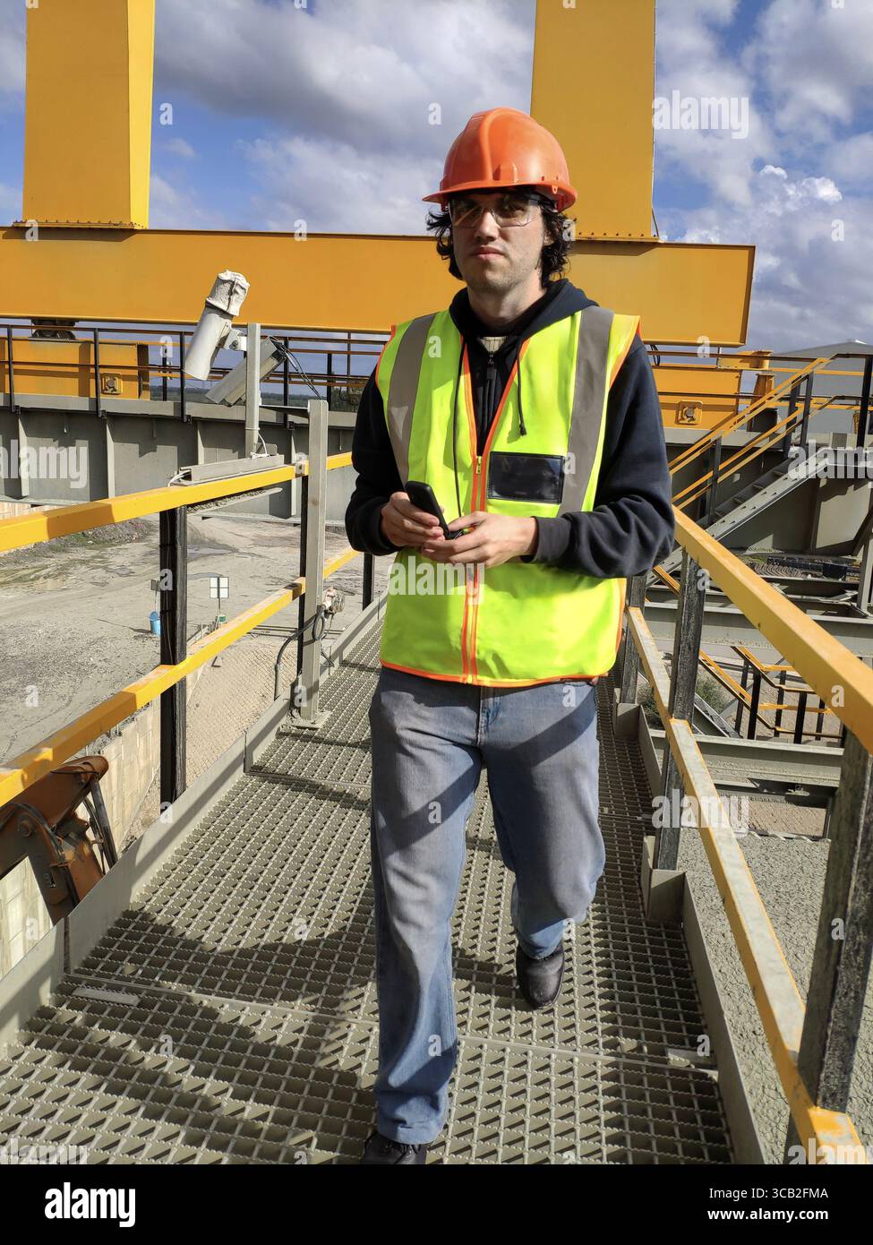 worker with reflective vest and safety helmet walking metal bridge on ...