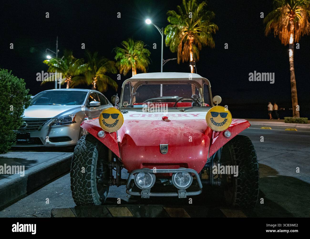 A classic red Meyers Manx dune buggy parked in central La Paz reflects ...
