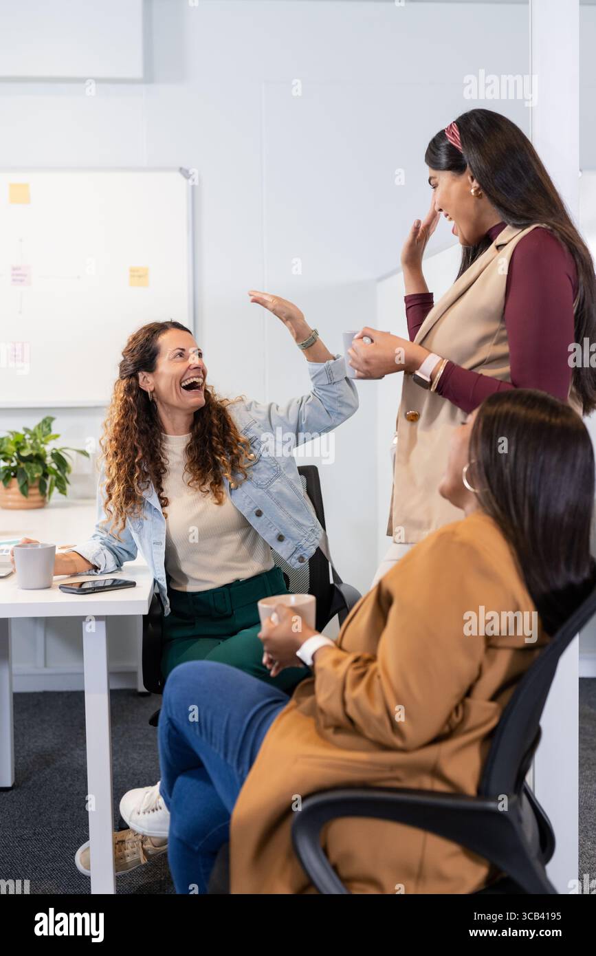 Diverse female coworkers in business attire exchanging high-five at ...