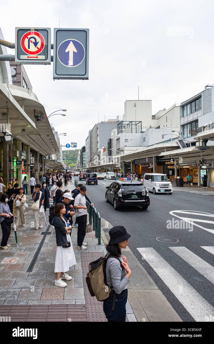 A bustling urban Kyoto street scene featuring pedestrians waiting to ...