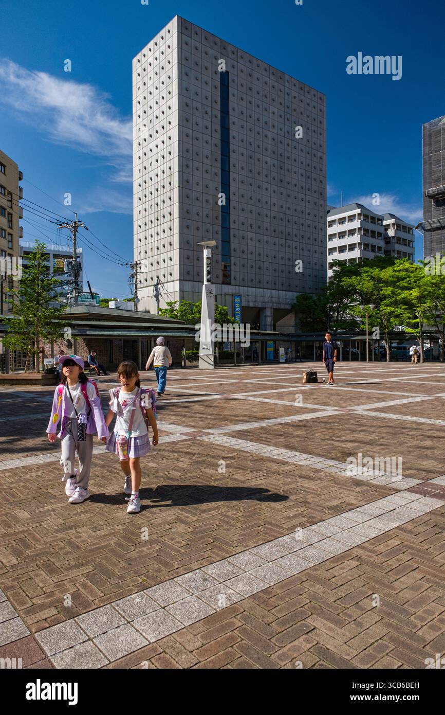 Two children walk through a sunlit urban plaza, surrounded by modern ...