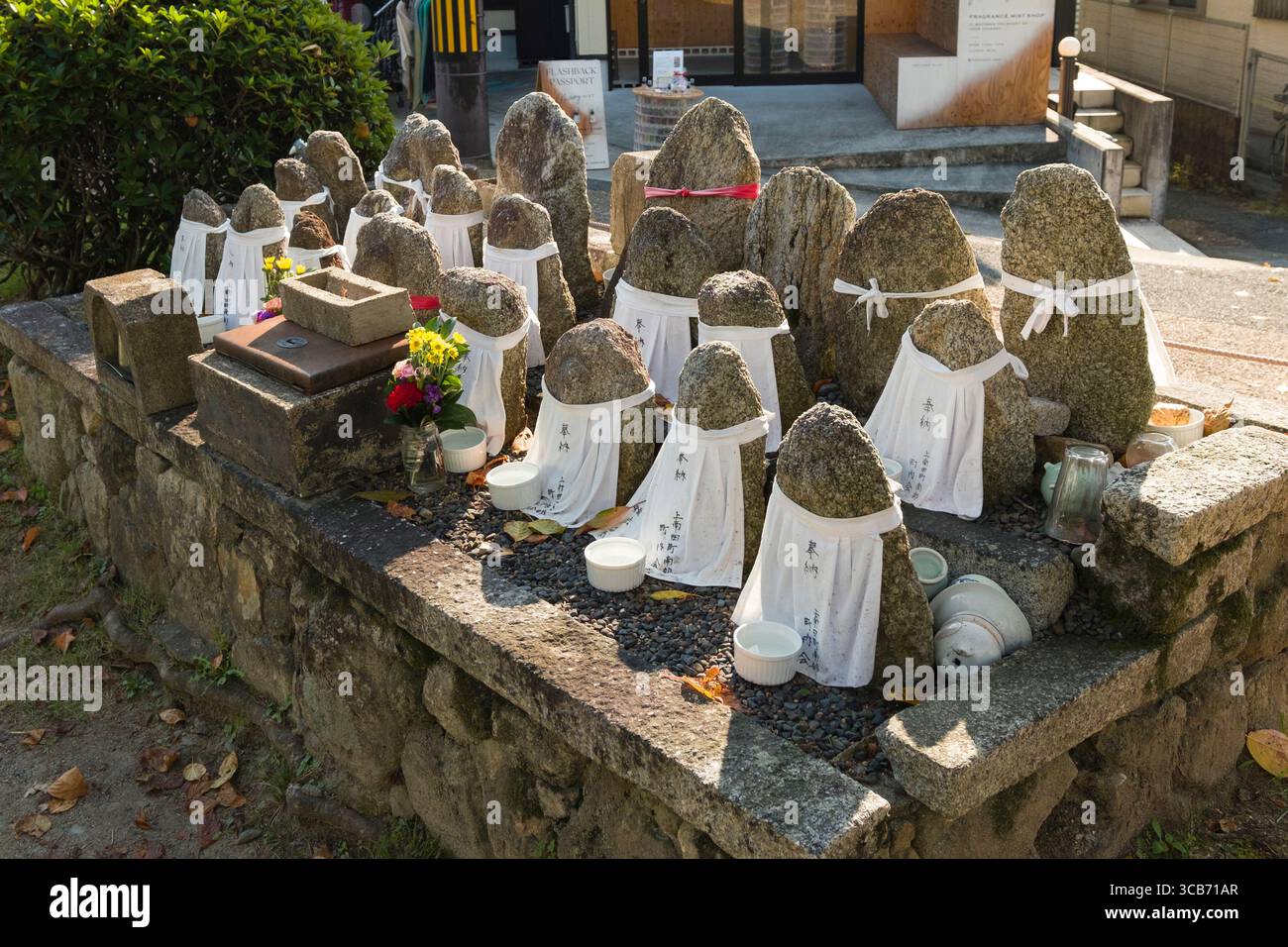 Stone monuments adorned with white cloths and offerings, representing ...