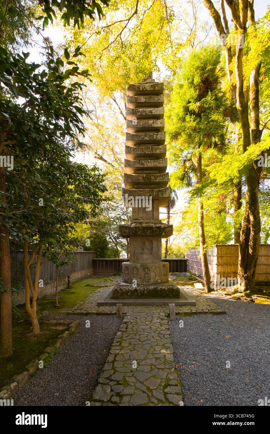 Stone pagoda on the grounds of Honen-in Temple, framed by vibrant trees ...