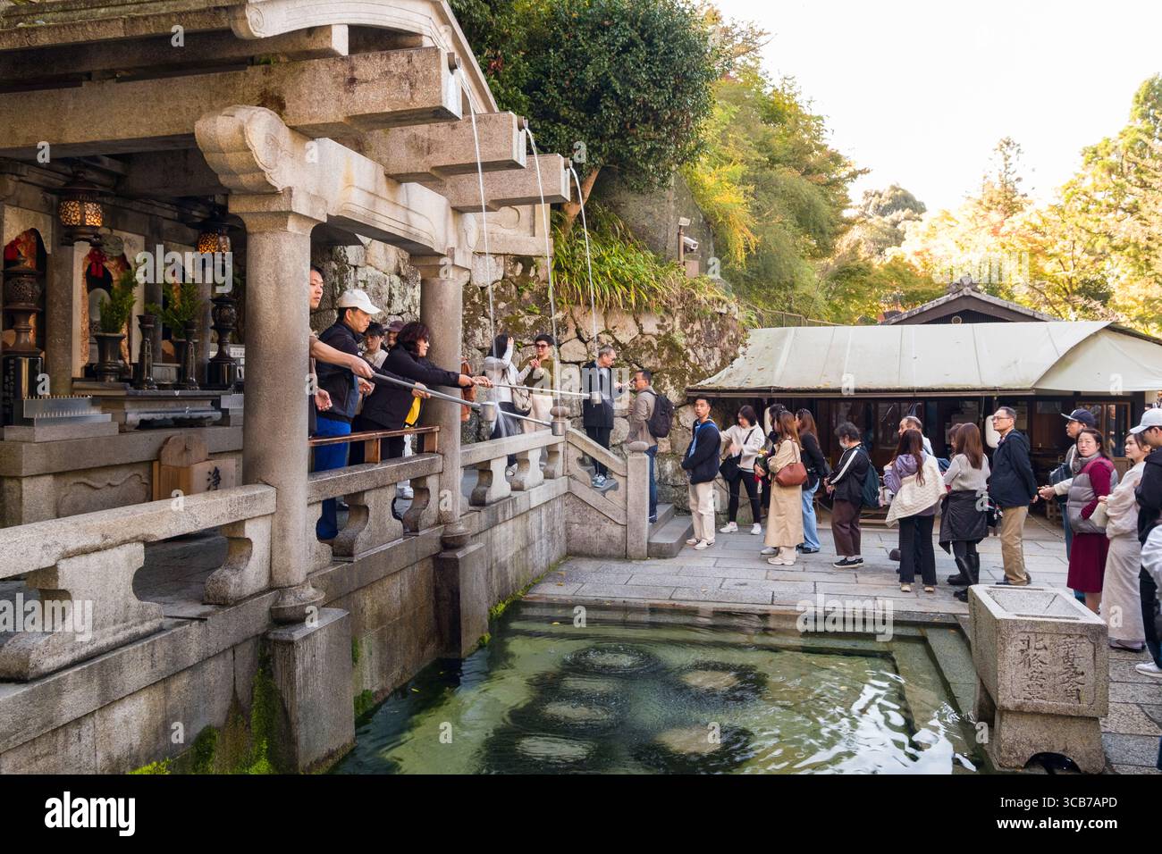 Tourist at Otowa Waterfall using ladles to collect sacred water ...