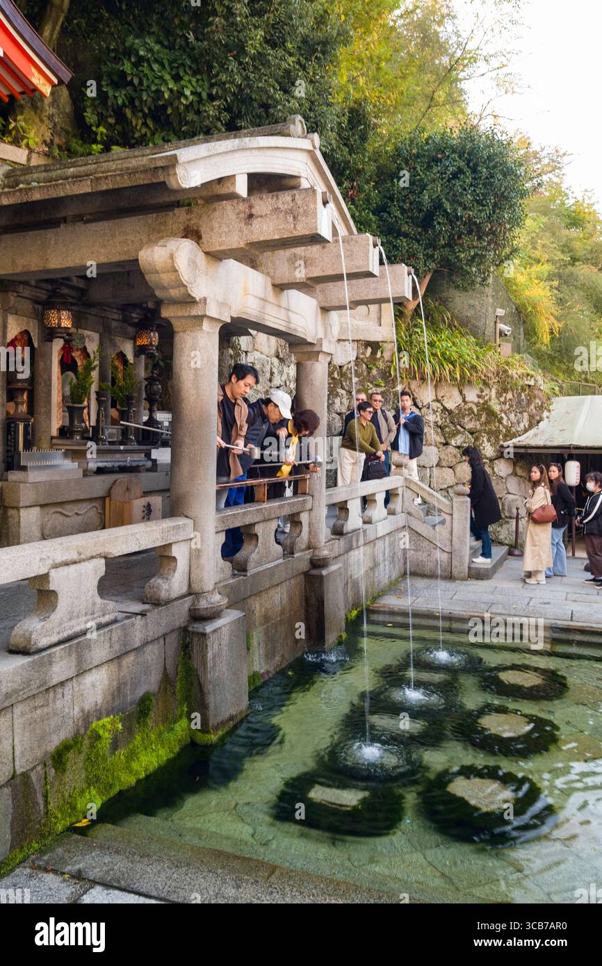 Tourist at Otowa Waterfall using ladles to collect sacred water ...