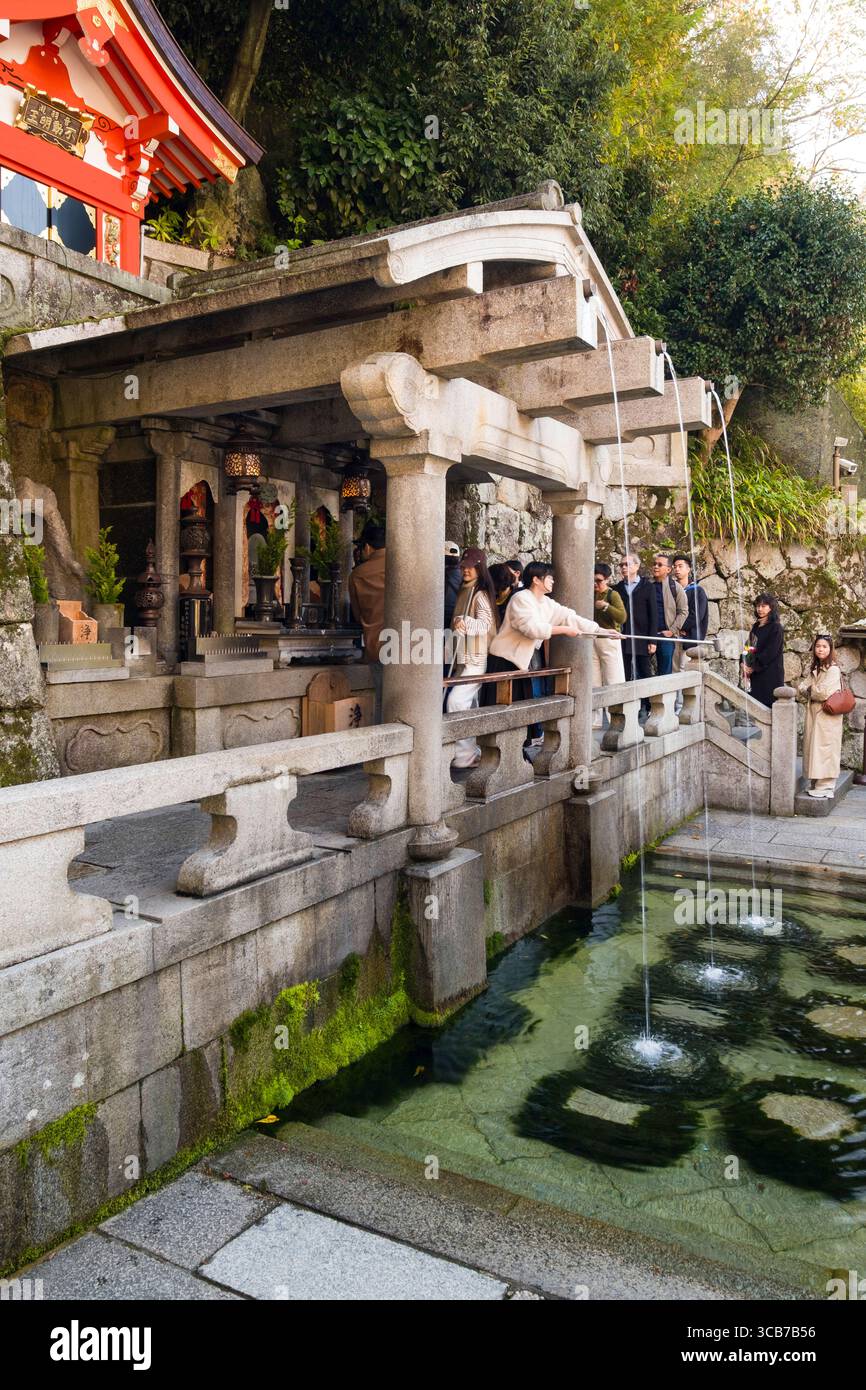 Tourist at Otowa Waterfall using ladles to collect sacred water ...