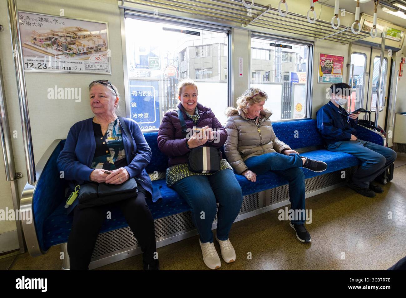 A group of people seated inside a public transportation train car ...