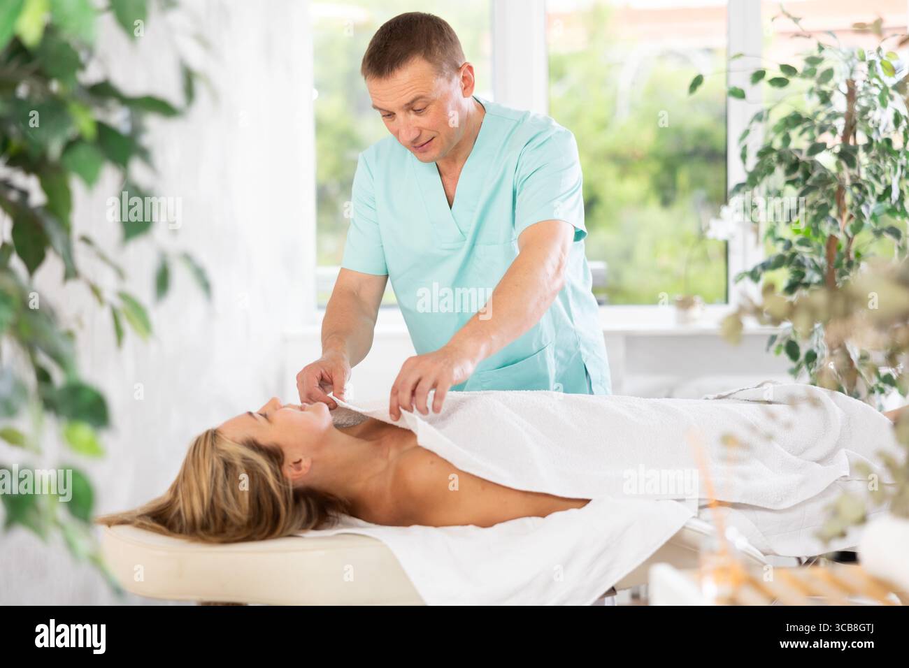 Male therapist covers woman client with white terry sheet after ...