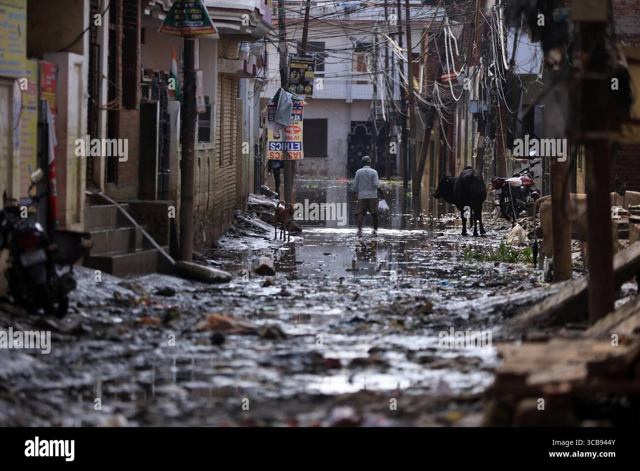 A man jumps across a mucky road at a flood-affected area as the water ...