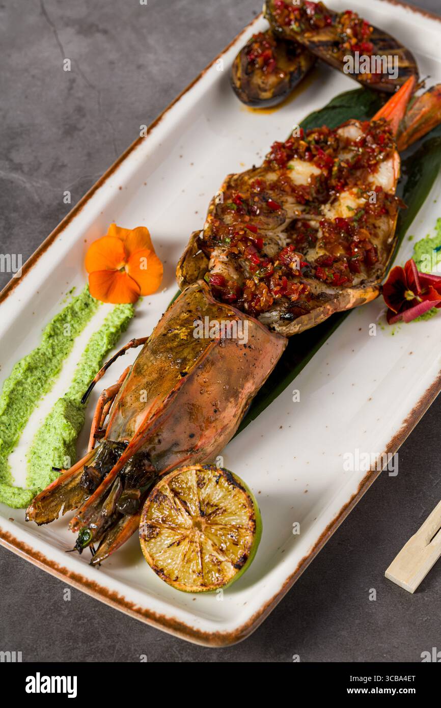 Grilled tiger shrimp served with green sauce, grilled lime, and herbs ...