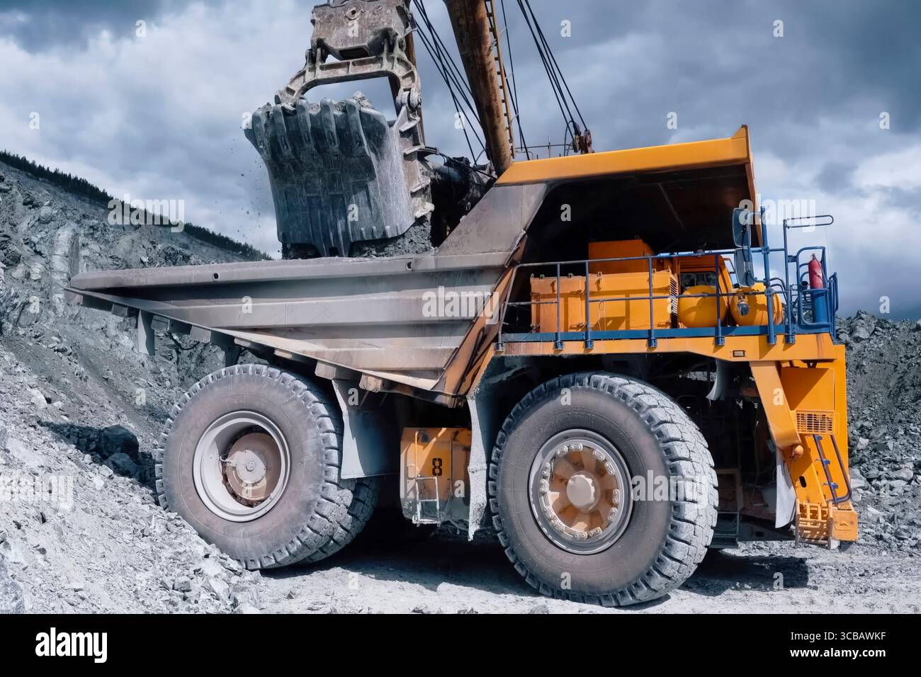 Yellow mining dump truck with crushed stone in the body, industrial ...