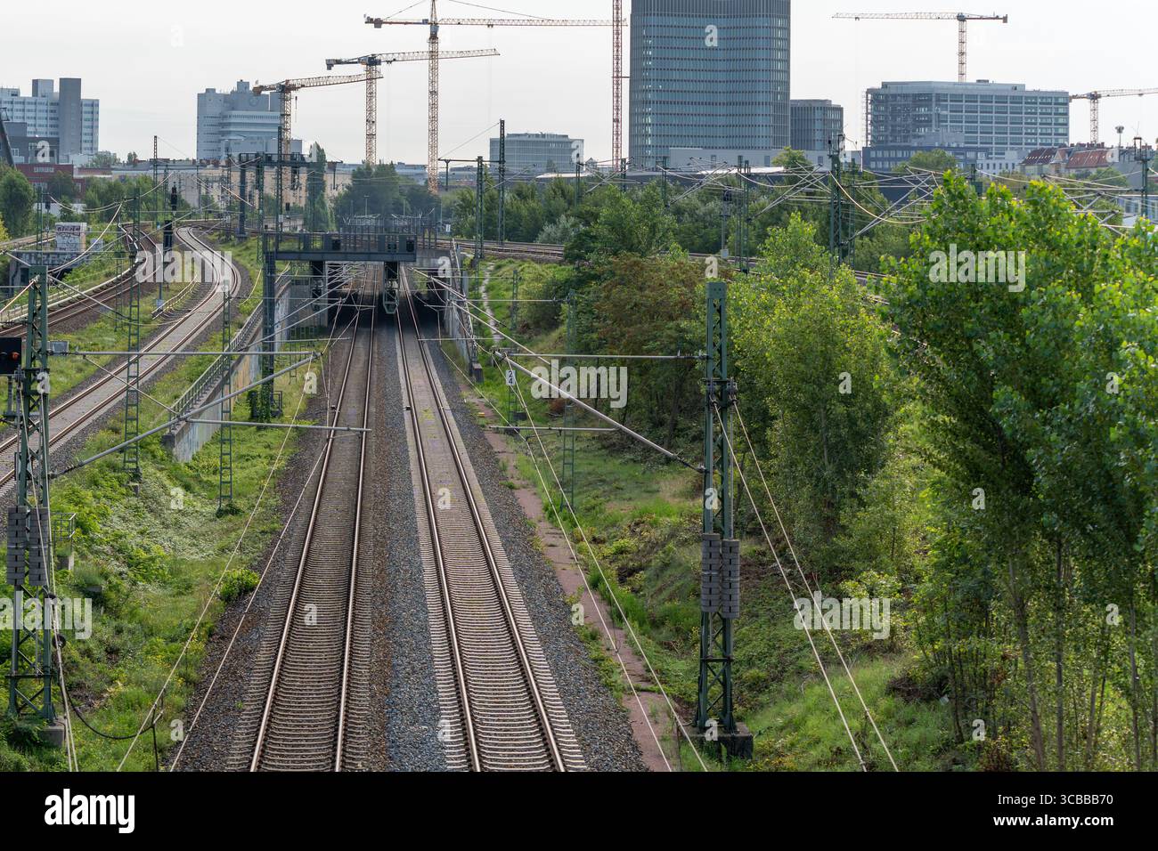 Railway tracks lead into a tunnel beneath a modern railway viaduct. The ...