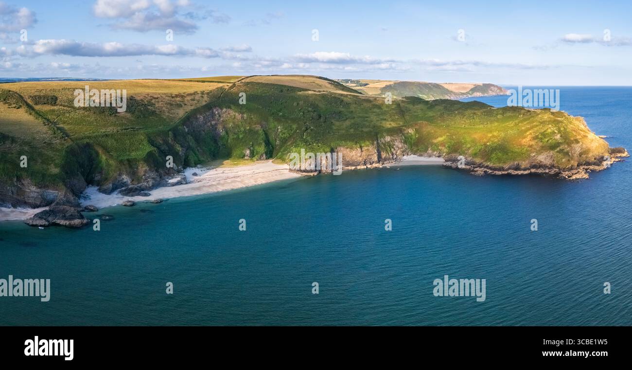 Aerial view of the coast where golden sunlight kisses the green cliffs ...