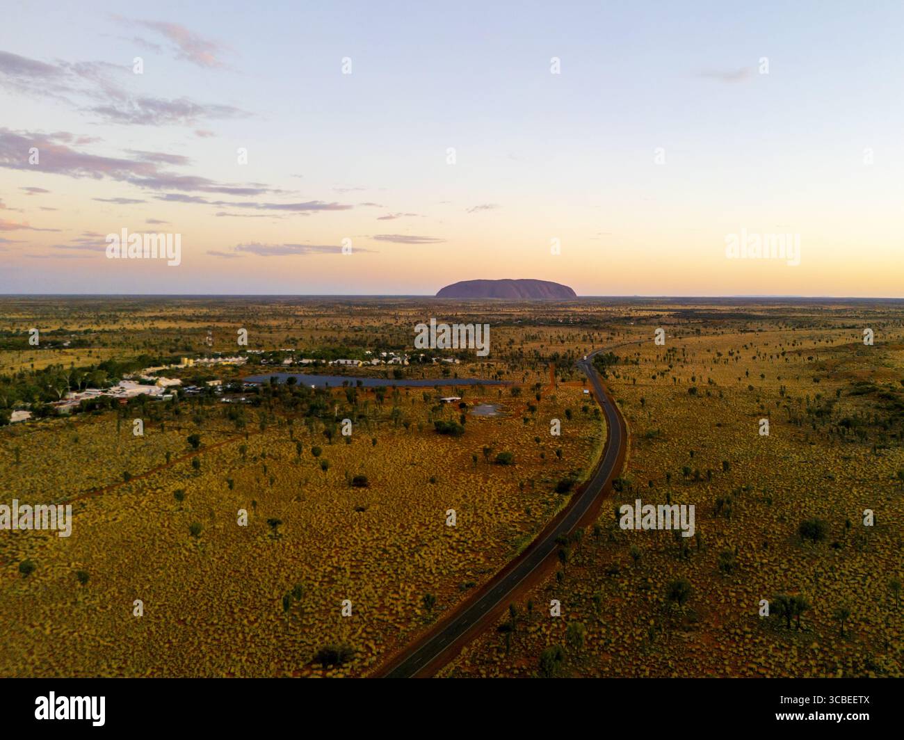 Aerial view of the iconic Uluru monolith piercing the horizon amidst ...