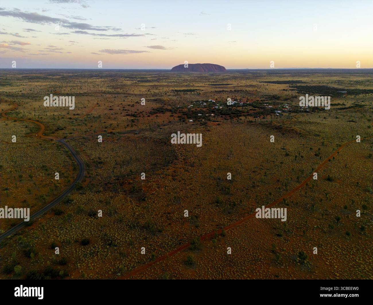 Aerial view of Uluru monolith rising majestically from the flat, arid ...