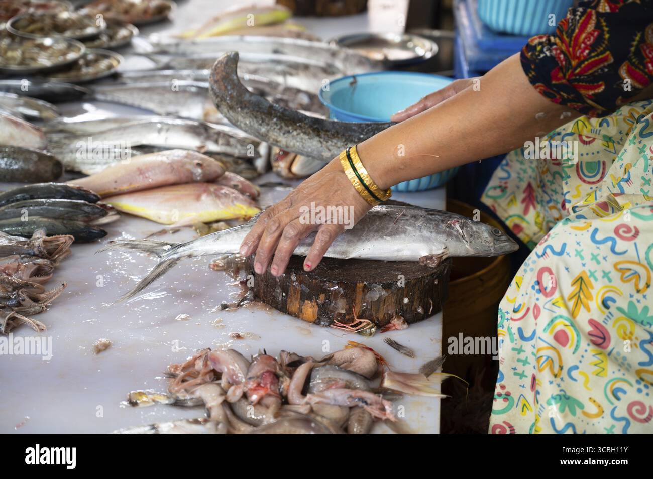 Indian woman cutting fish on a market in Mumbai India, sales stall with ...