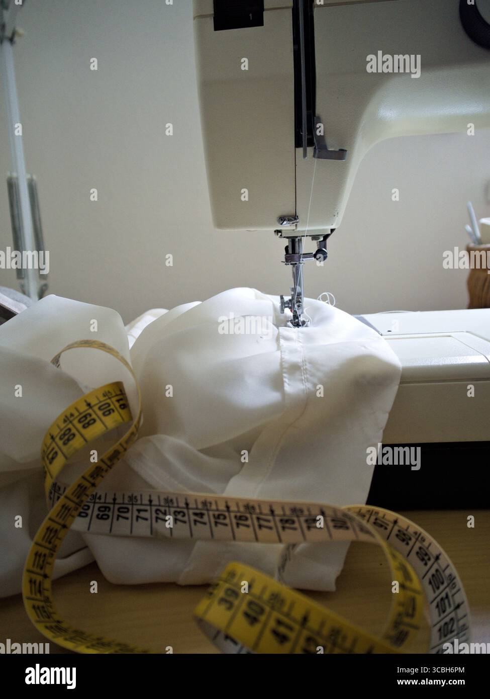 Industrial sewing machine stitching white fabric with measuring tape ...