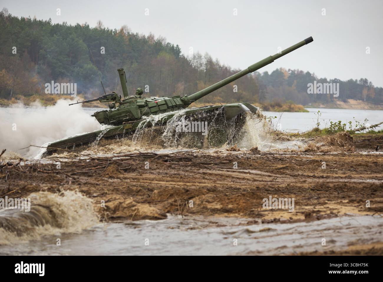 A powerful heavy fighting vehicle tank leaves the river bank after ...