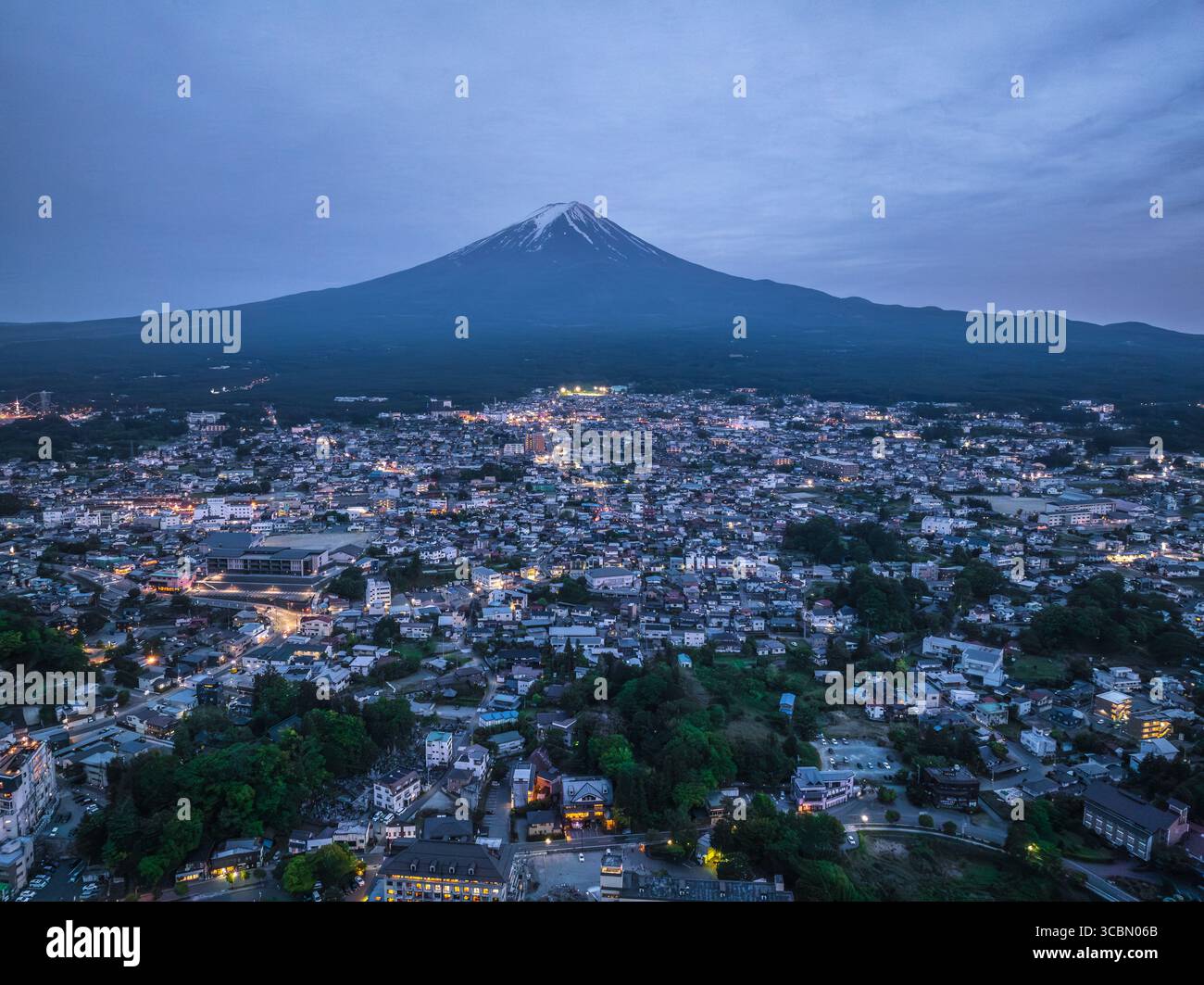 Aerial view of Mount Fuji looming majestically over a sprawling town ...