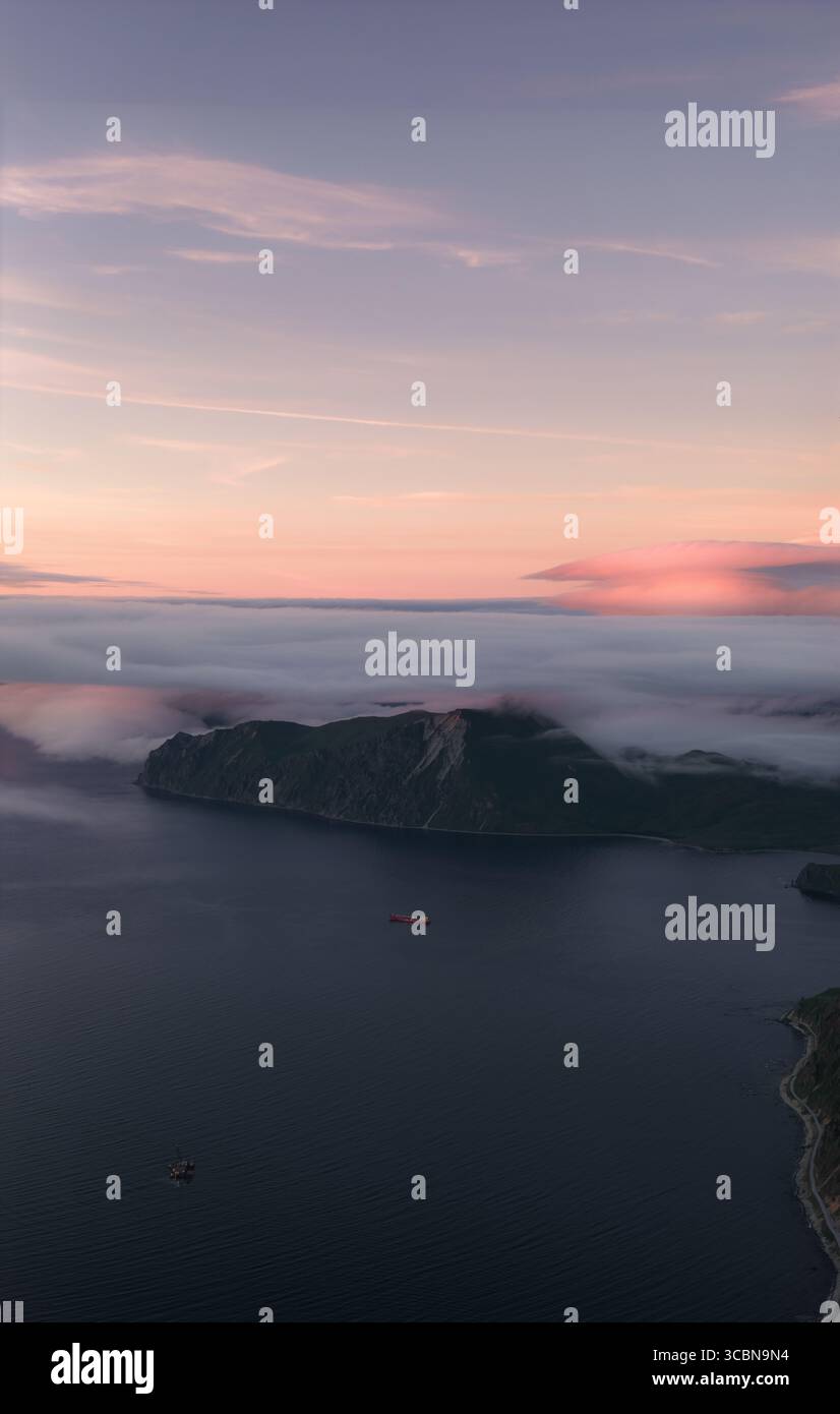 Aerial view of where the dark sea meets the rugged, cloud-kissed land ...