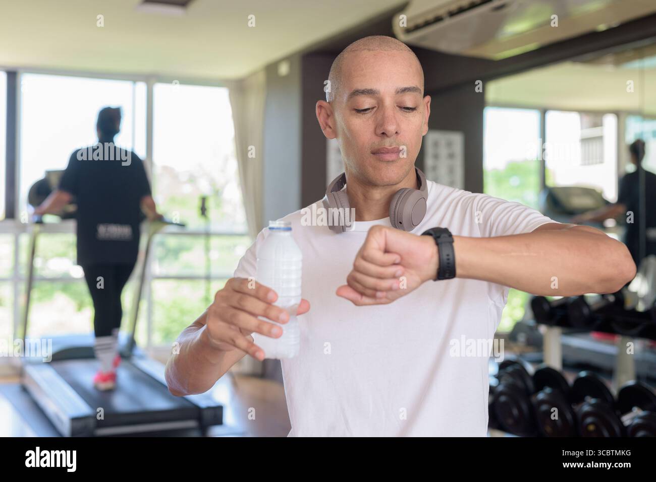 Bald Latino man standing inside modern gym with confident expression ...