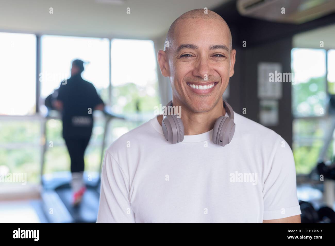 Bald Latino man standing inside modern gym with confident expression ...