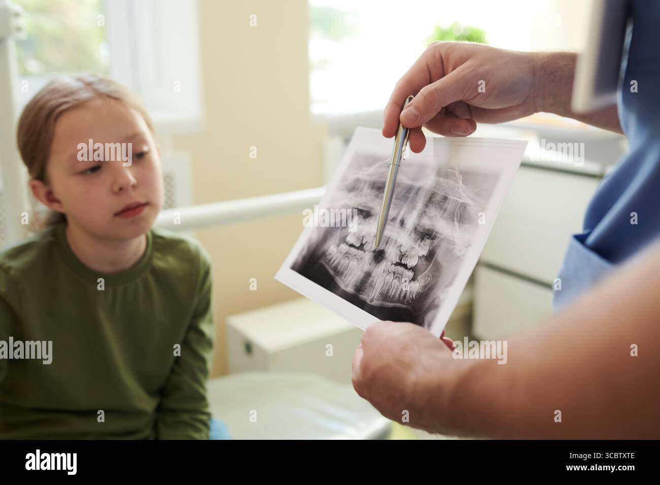 Caucasian girl child sitting in medical office observing male doctor ...