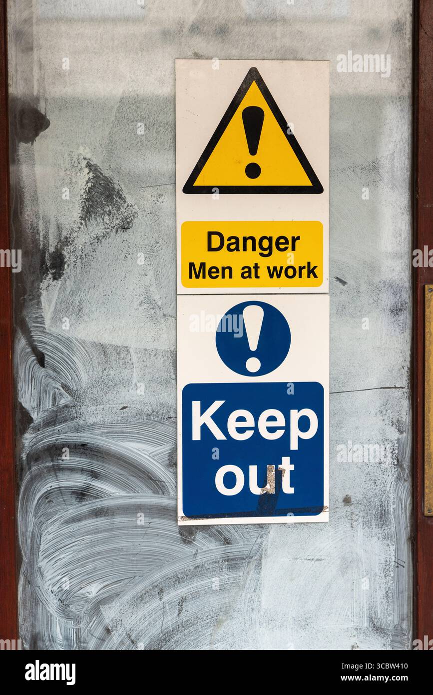 Danger Men at work and Keep out safety warning signs on a glass door in ...