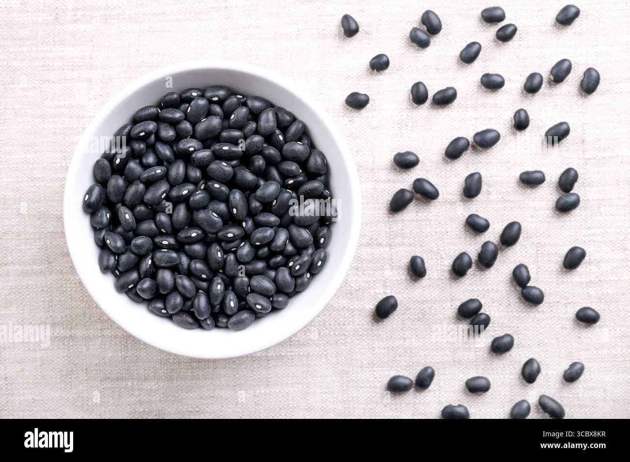 Black beans, in a white bowl, on linen. Dried variety of common beans ...