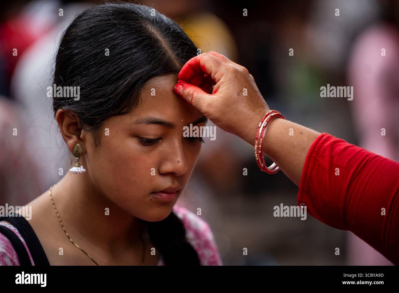 Lalitpur, Nepal. 9th Aug, 2025. A devotee receives tika on her forehead ...